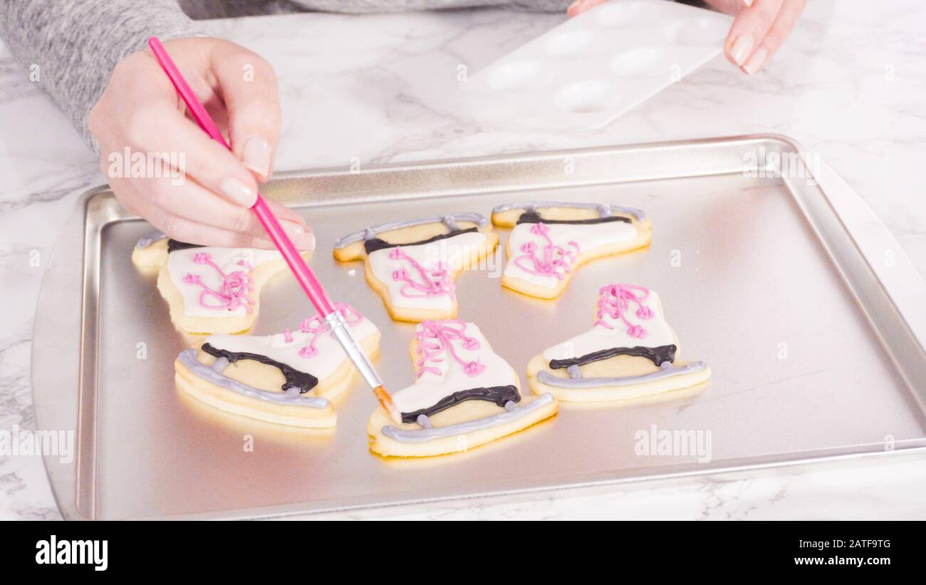 Brushing edible glitter on iced figure skate sugar cookies Stock Photo ...