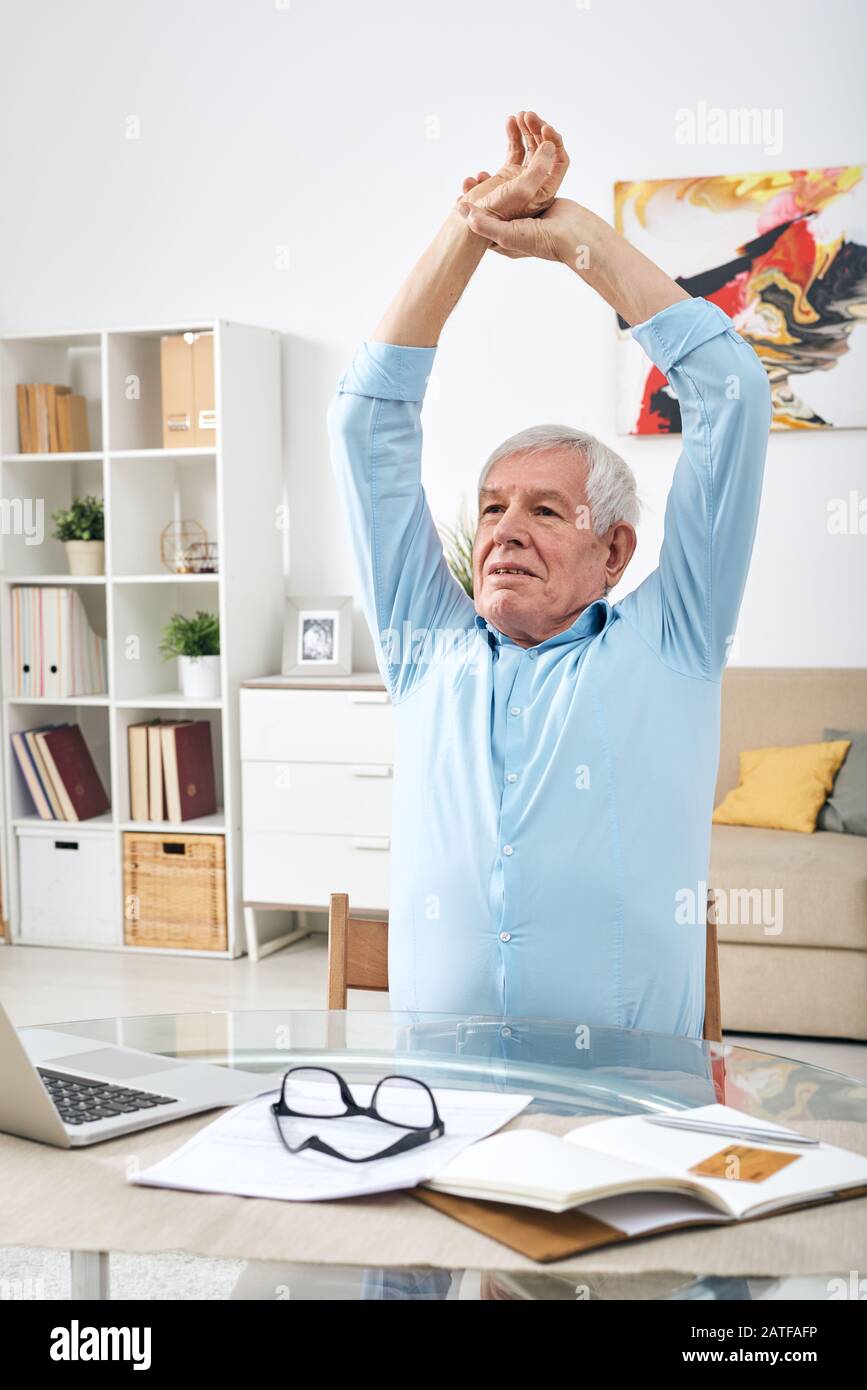 Senior slightly tired man raising his hands over head while exercising ...