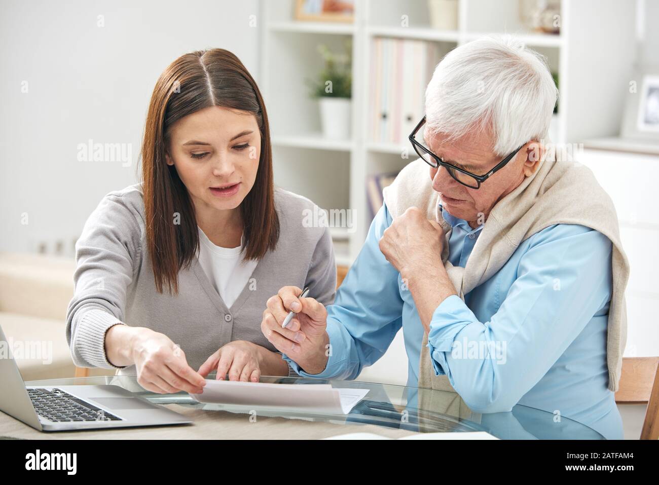 Young female explaining her senior father how to fill in paper Stock ...
