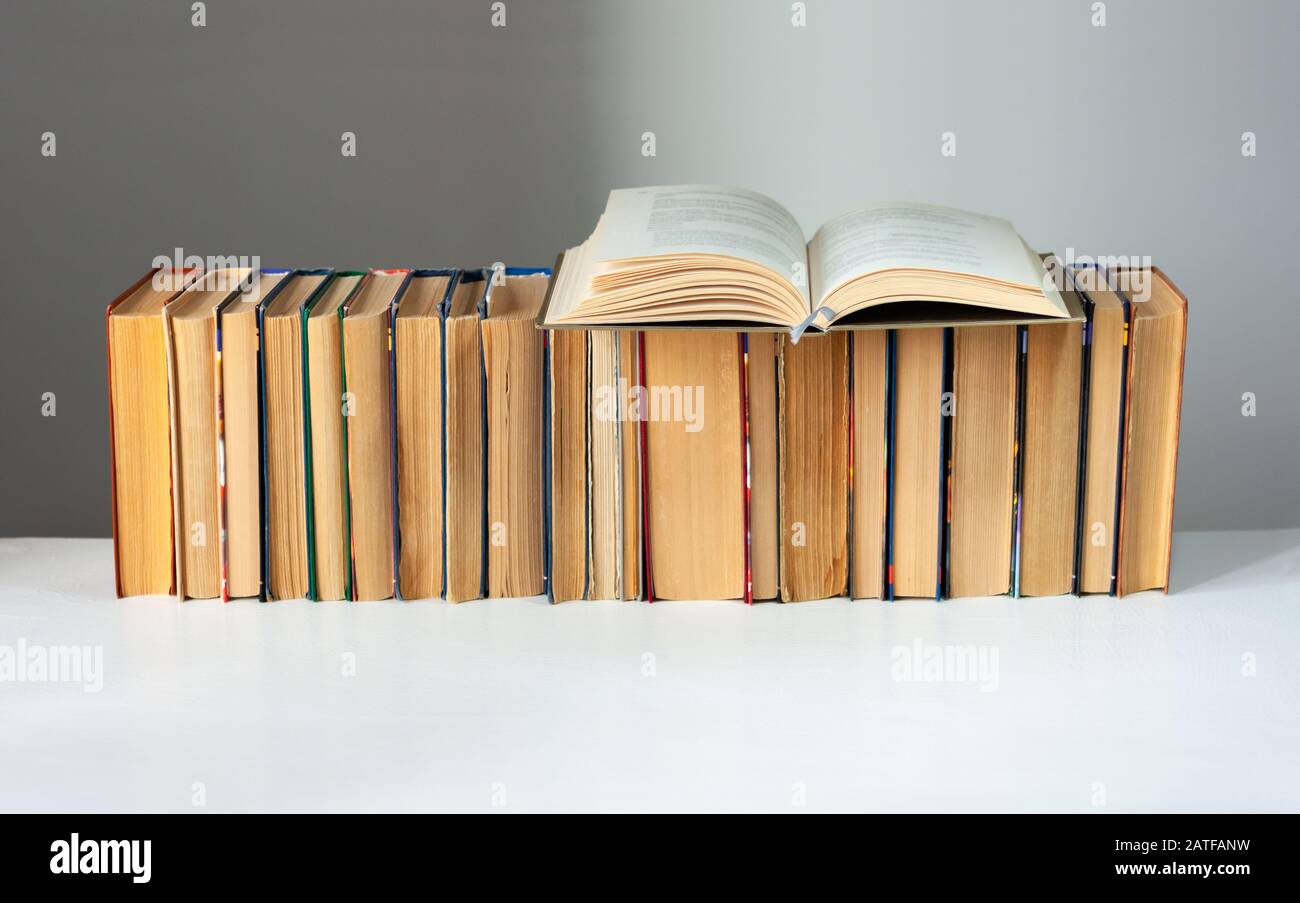Open hardback book, diary, fanned pages on stack of books on white ...