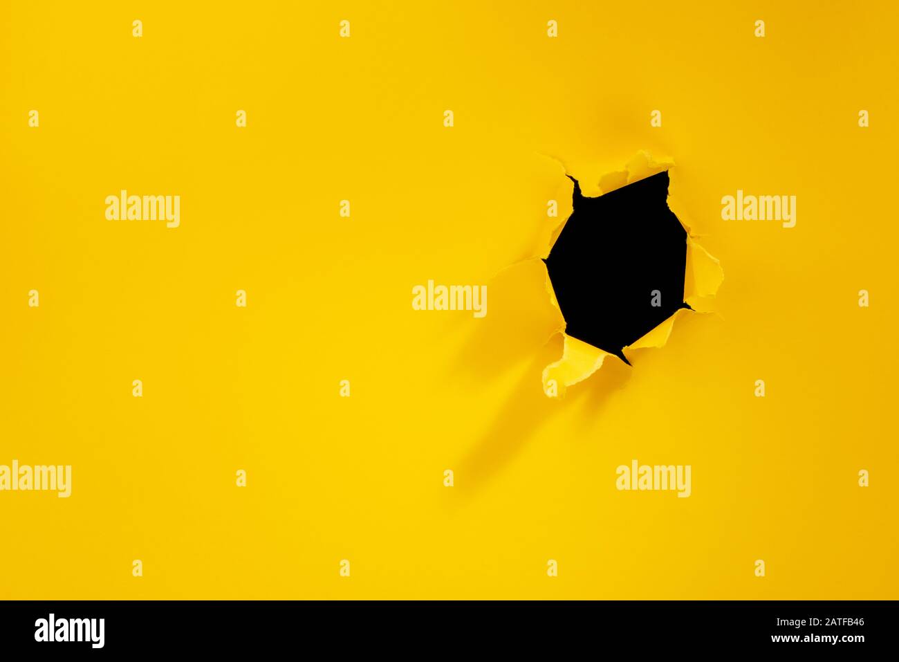Torn hole in yellow paper background Stock Photo - Alamy