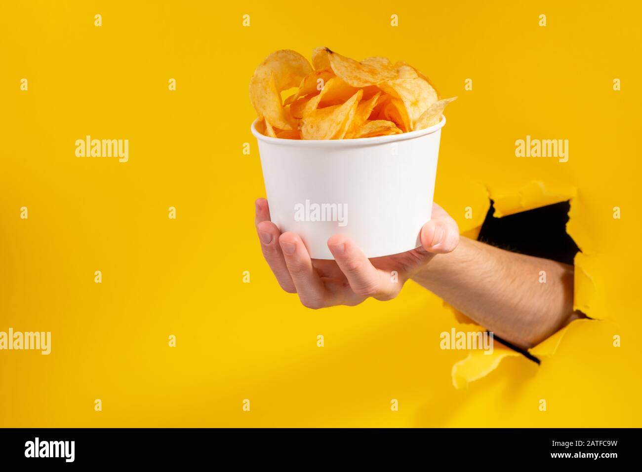 Hand giving a cup of potato chips Stock Photo - Alamy