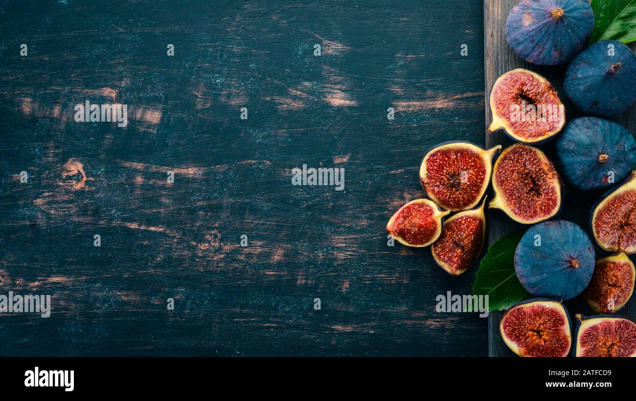 Figs on a wooden board. Slice figs. On a dark background. Free space ...