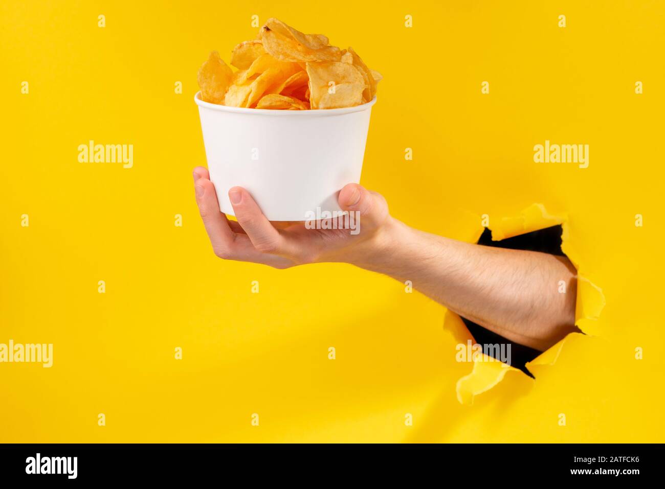 Hand giving a cup of potato chips Stock Photo - Alamy