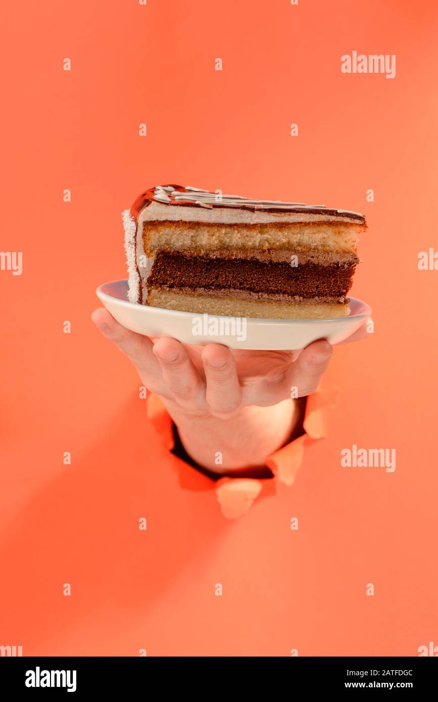 Hand holding a piece of cake on a plate Stock Photo - Alamy
