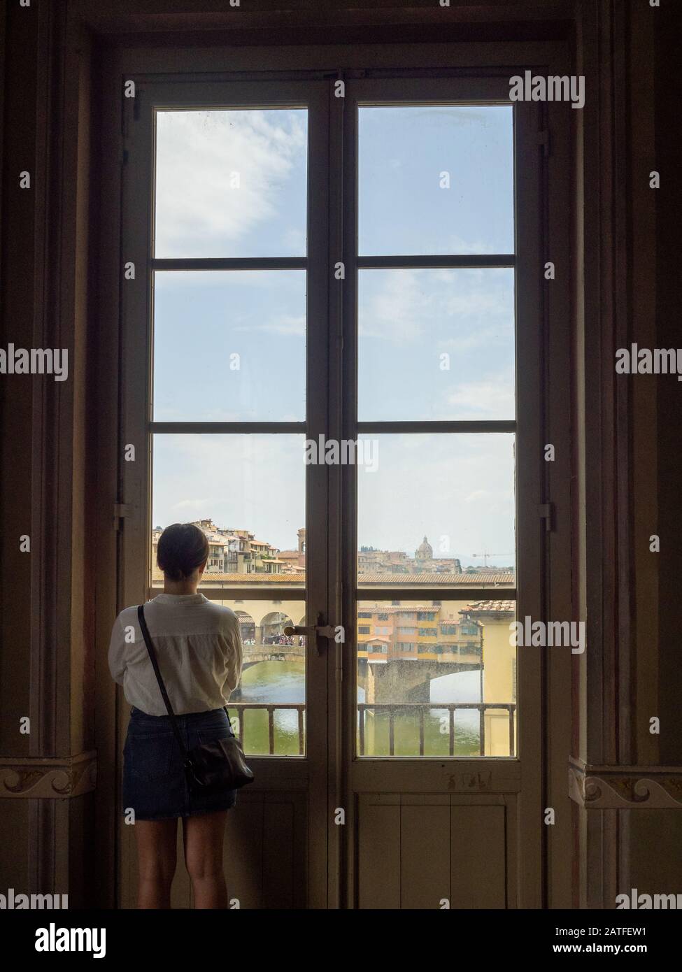 A tourist looks at Ponte Vecchio from inside the Uffizi Galleries ...