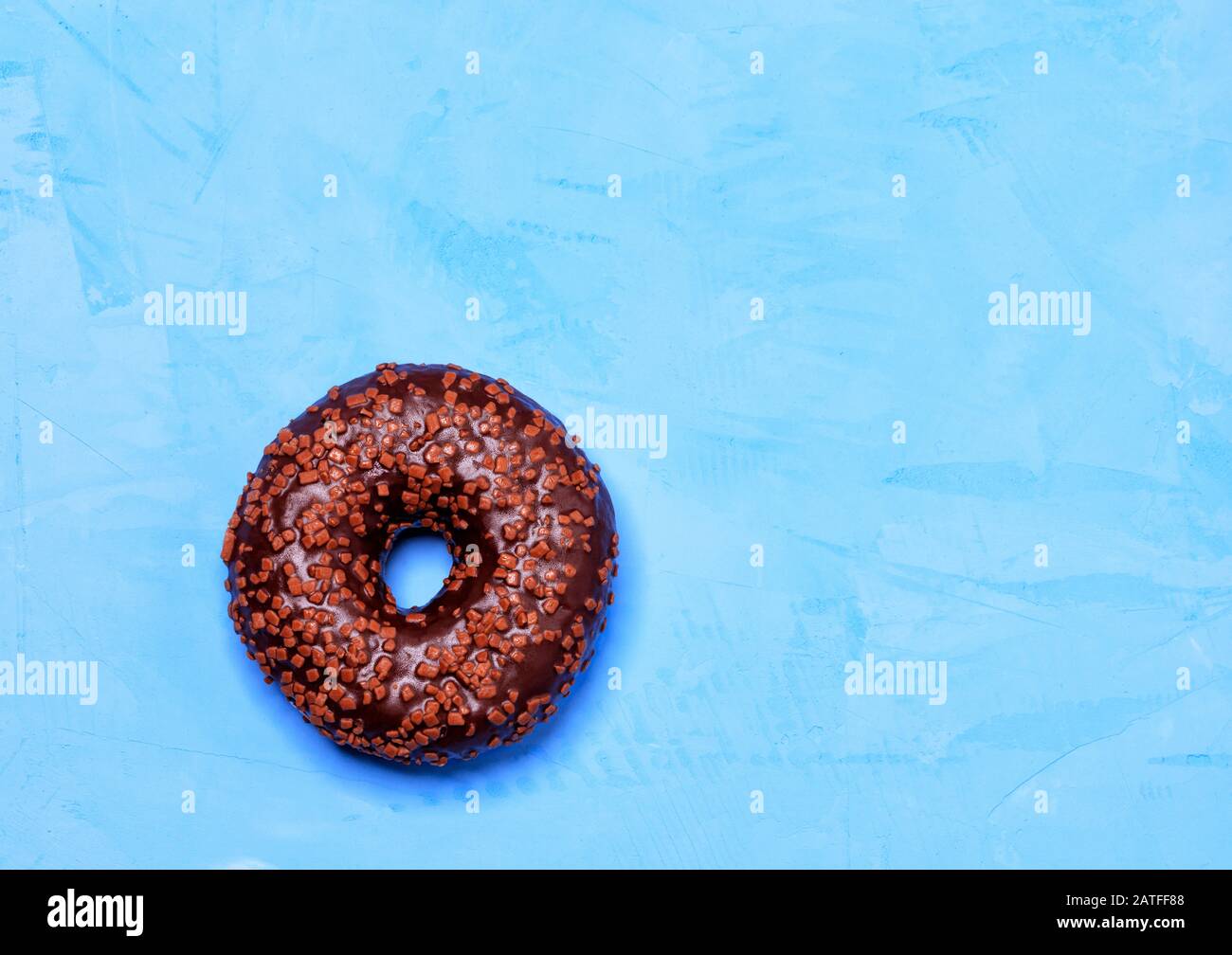 Delicious chocolate donut on a blue concrete surface in cold light ...