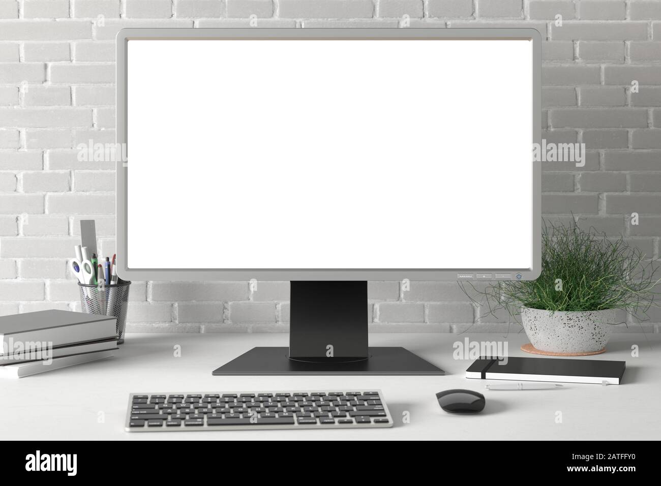 Workspace with blank computer monitor white screen mock up on the white desk near white brick ...