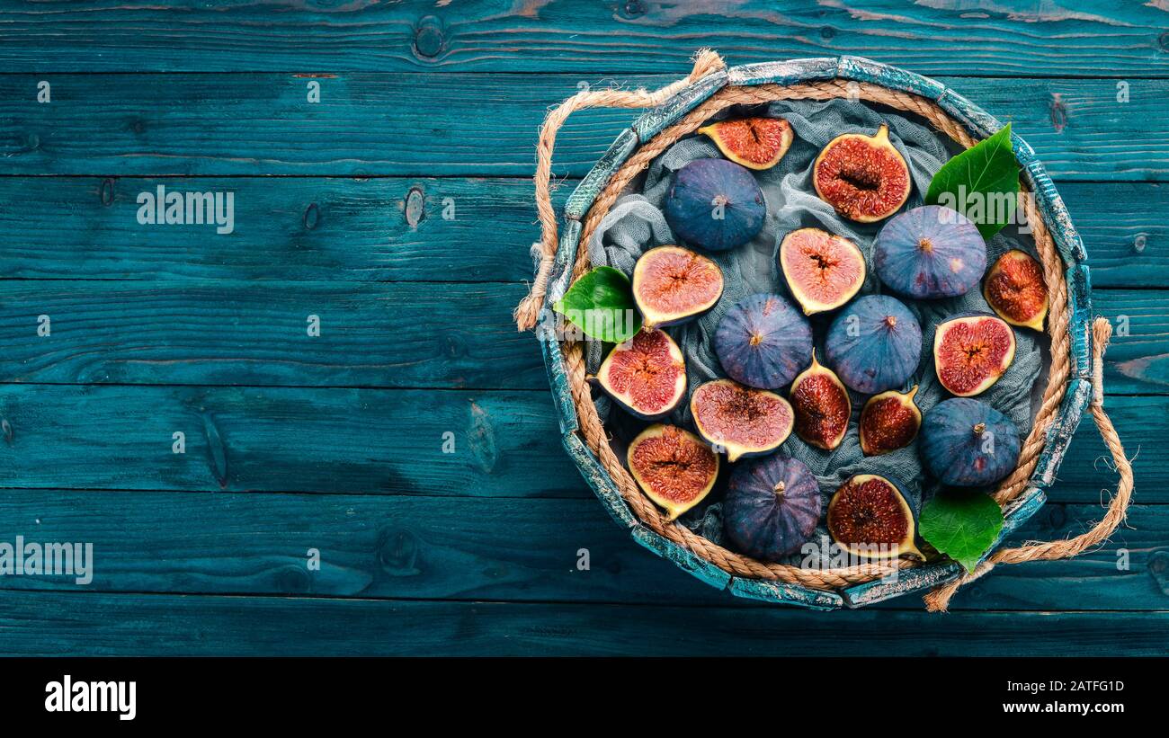 Fresh figs in a wooden box on a blue background. Free space for text ...