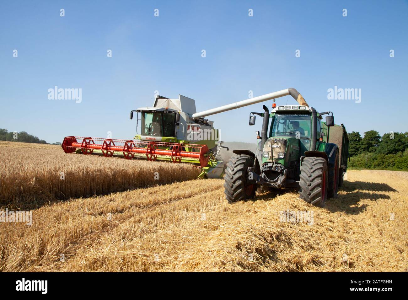 Combine Harvester and tractor together harvesting on a summers day ...