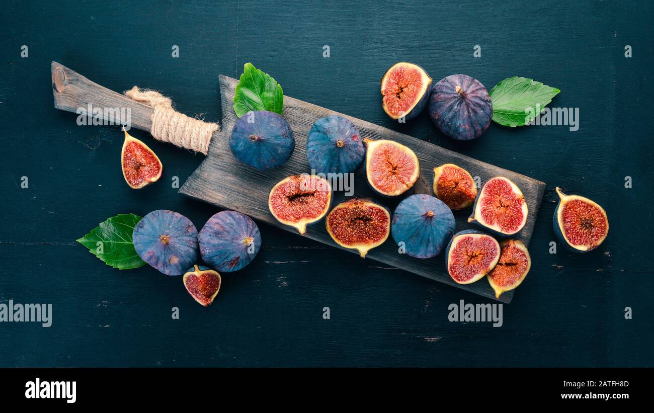 Figs on a wooden board. Slice figs. On a dark background. Free space ...