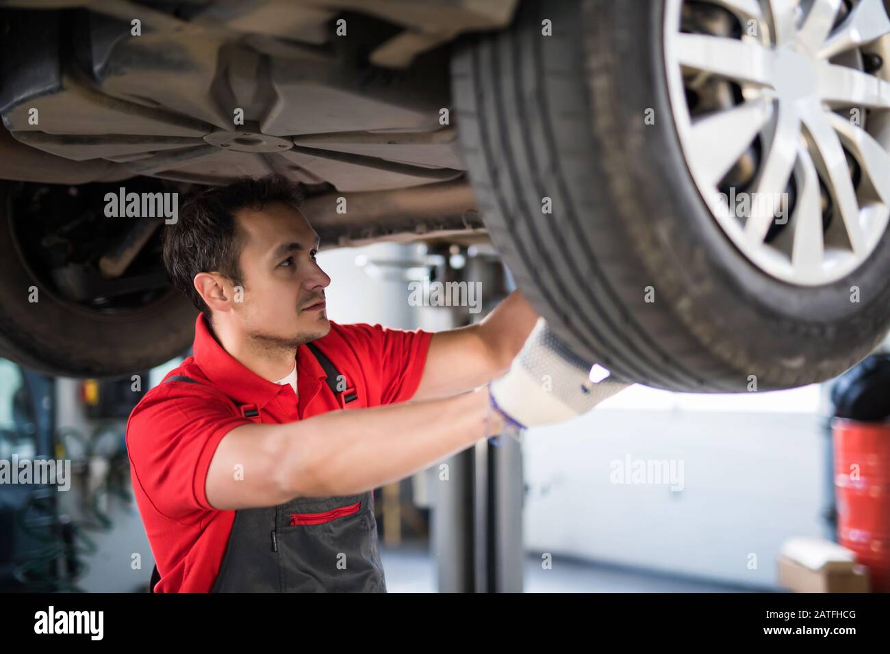 Professional car mechanic man working under lifted car in auto repair ...