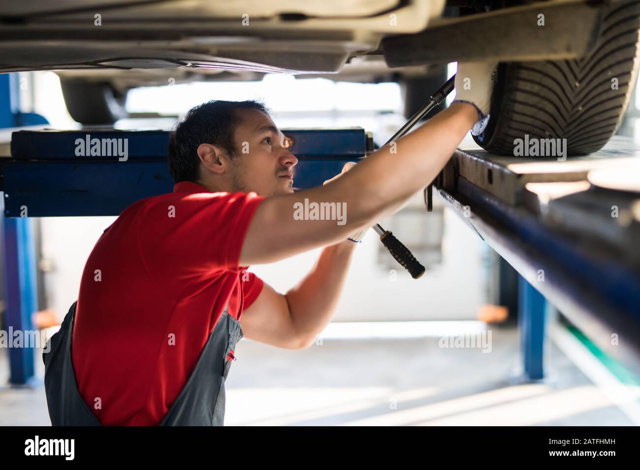 car mechanic with spanner tighten car suspension detail of lifted ...