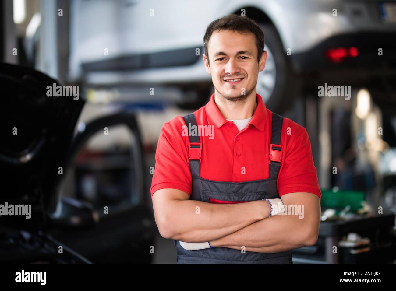 Portrait of a young beautiful car mechanic in a car workshop, in the ...