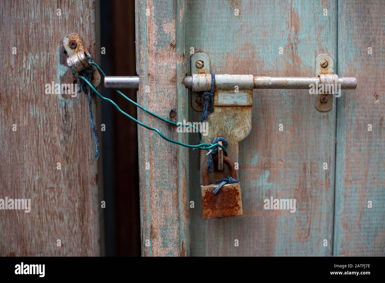 A landscape photo of a classic, rusty metal latch on an old wooden gate ...