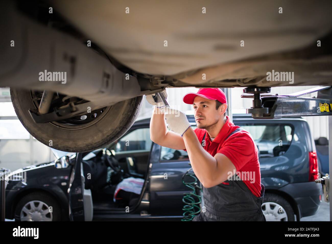 car mechanic with spanner tighten car suspension detail of lifted ...
