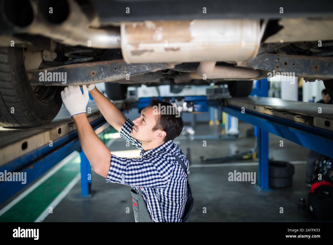 Portrait of a mechanic repairing a lifted car Stock Photo - Alamy