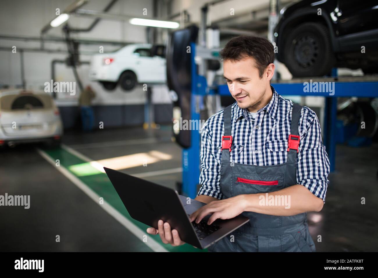 Mechanic using computer diagnostics while repairing car Stock Photo - Alamy