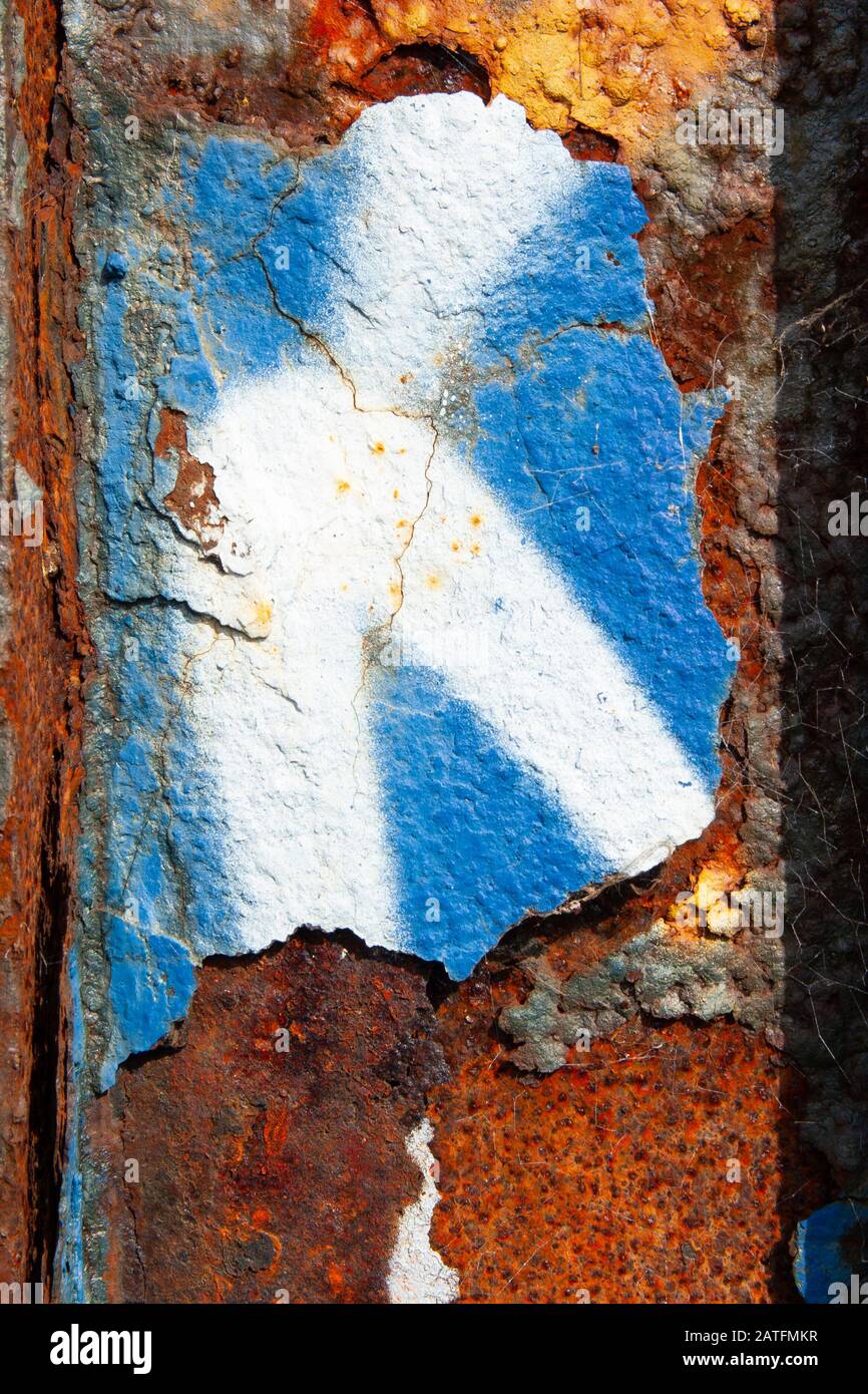 White letter with tilde scratched rusty metal background, blue stencil ...