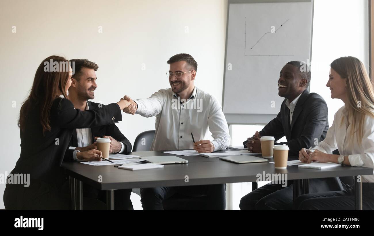 Businesspeople gathered in conference room shaking hands showing ...