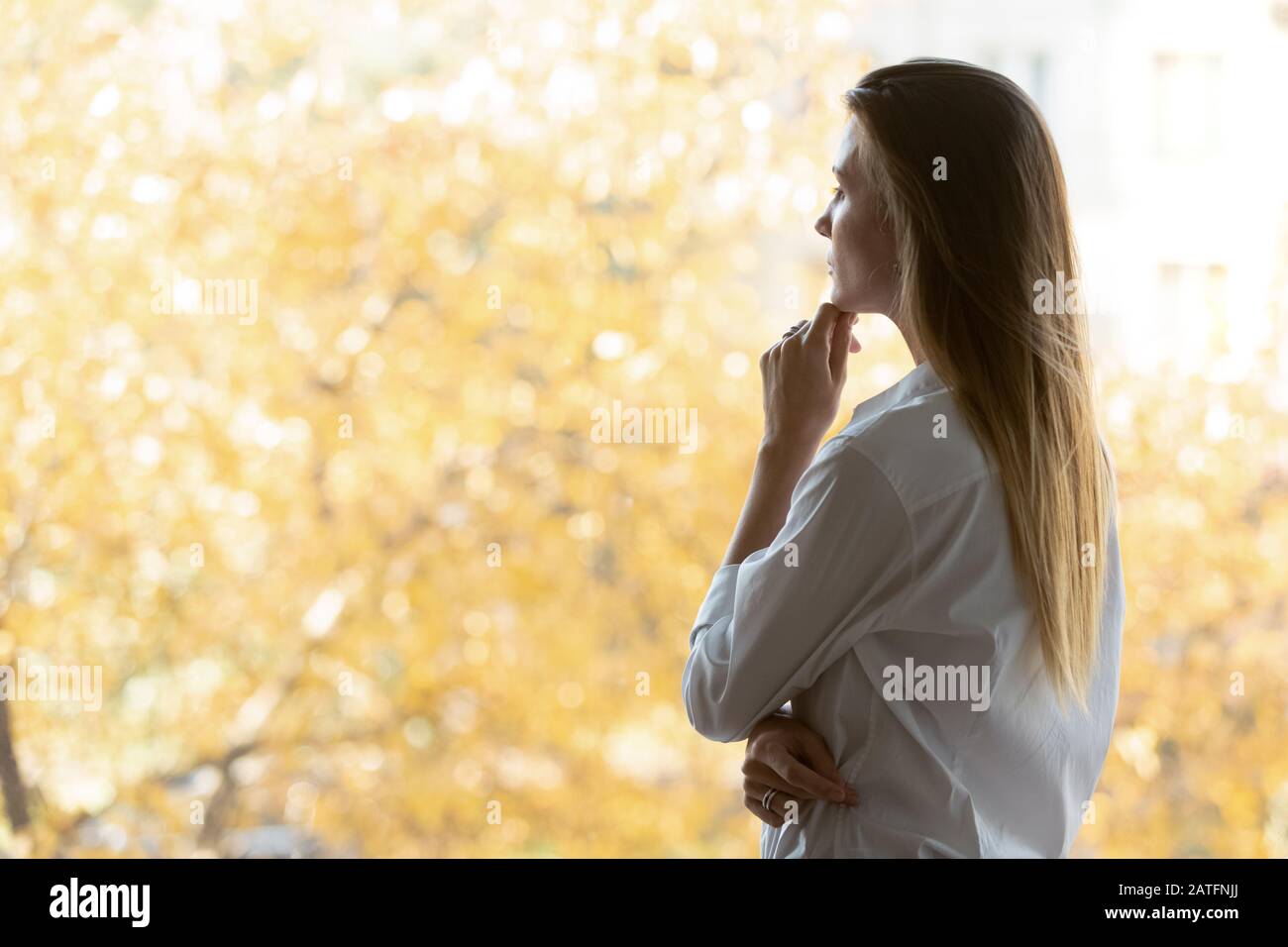 Pensive businesswoman standing in office looking out window search ...