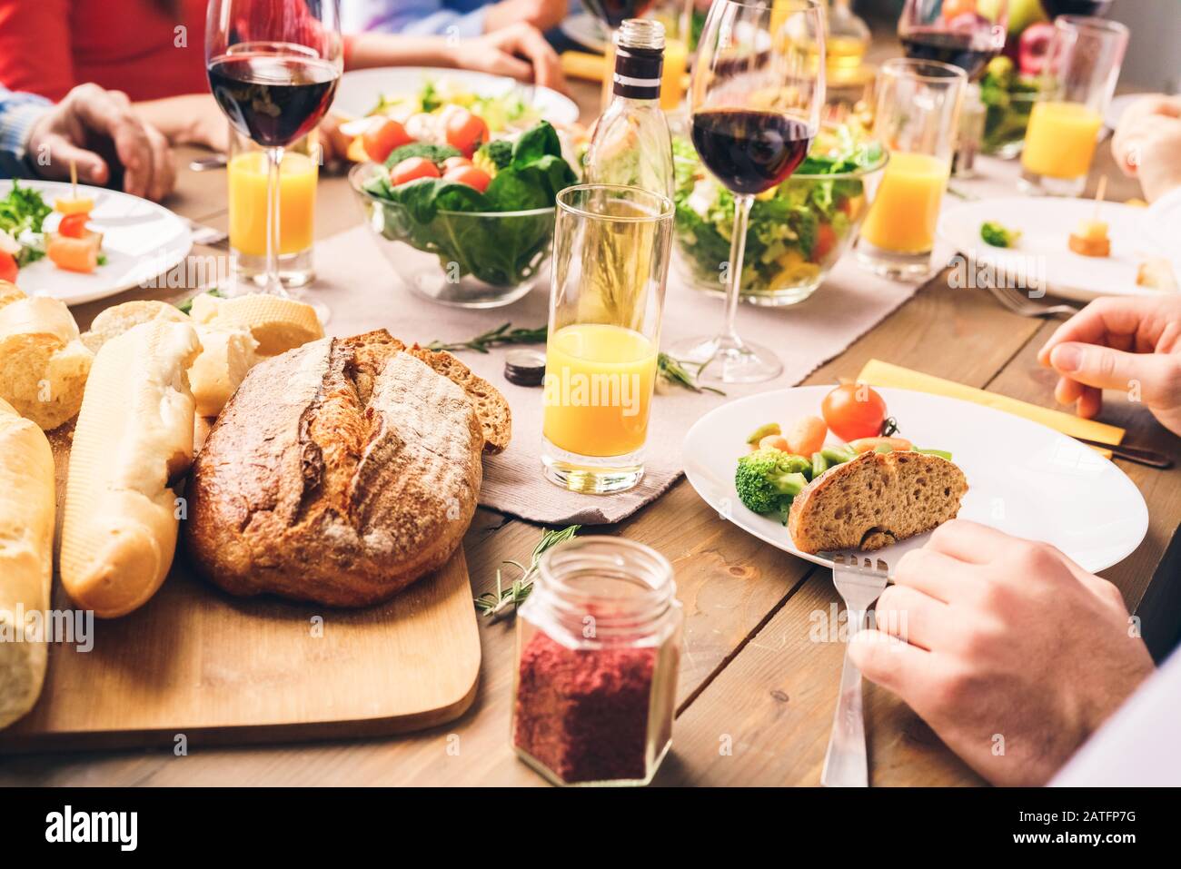 People sitting at home behind table, eating delicious food Stock Photo ...