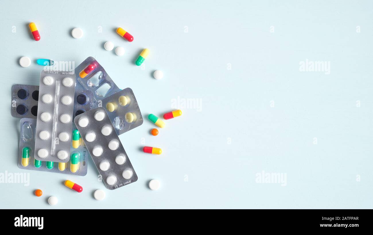 Colorful capsules and medical tablets over blue background with copy ...