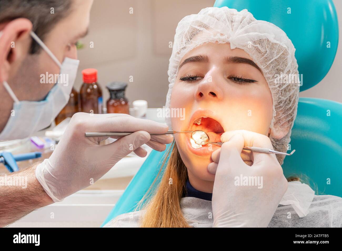 dentist checks the lower teeth of the patient with a mirror and a spike ...