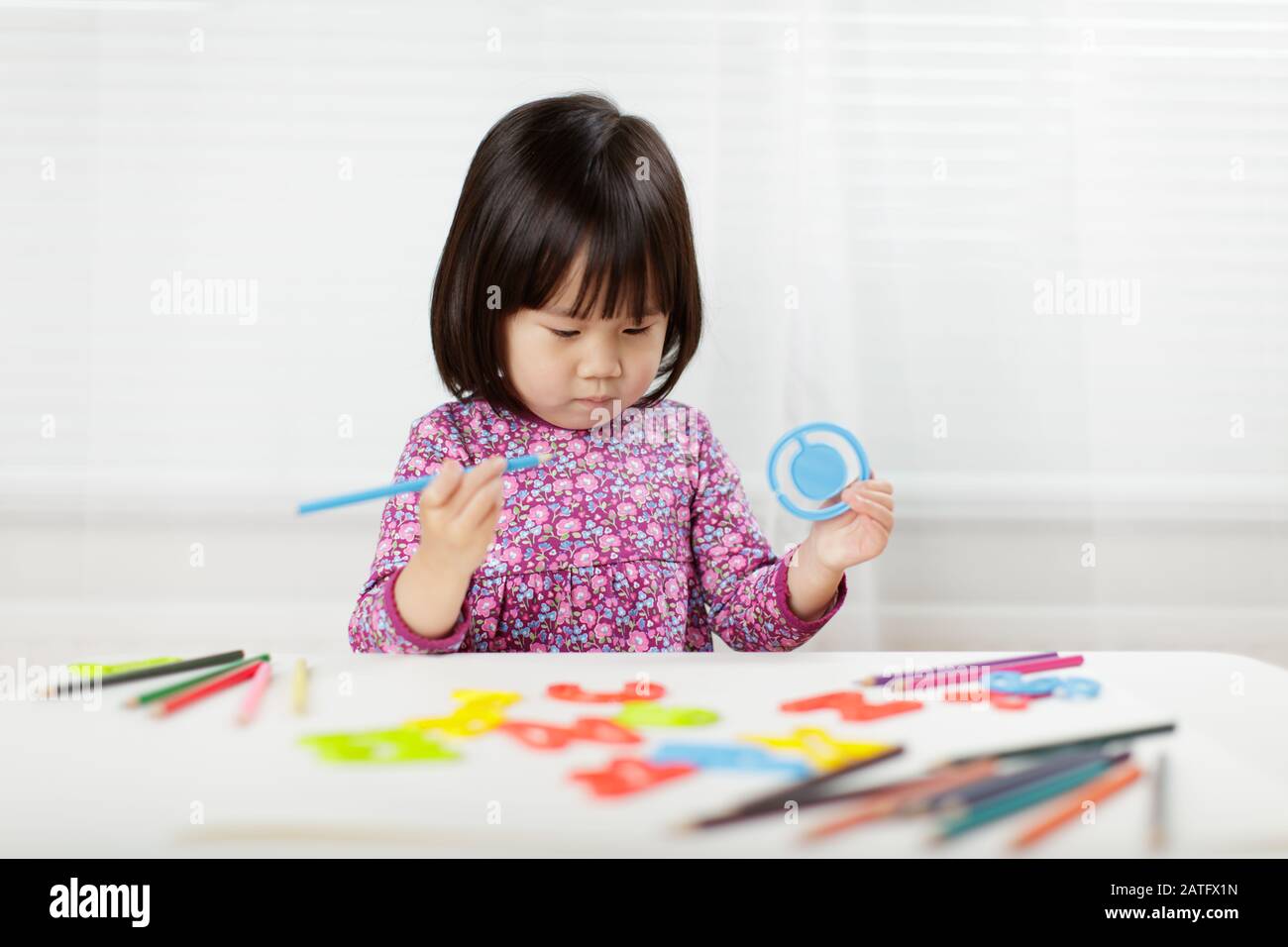 toddler girl practice writing letters on white paper against white ...