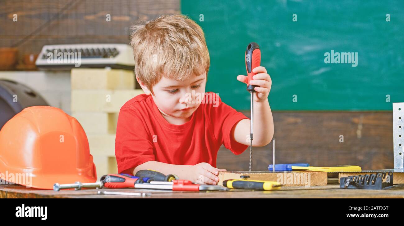 Kid learning to use screwdriver. Concentrated kid working in repairs ...