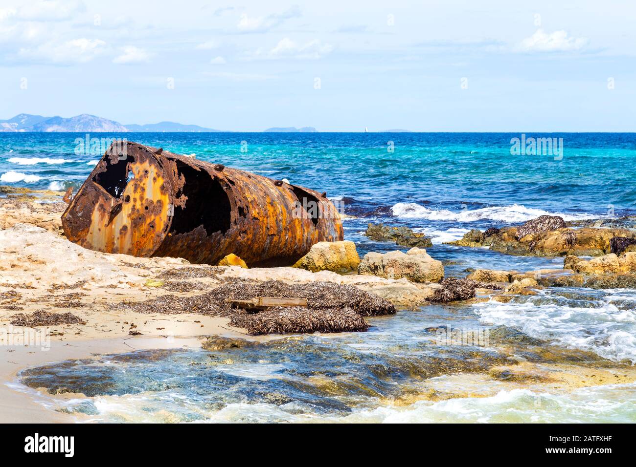 Rusty barrel container washed ashore at S'Espalmador Island, Balearic ...