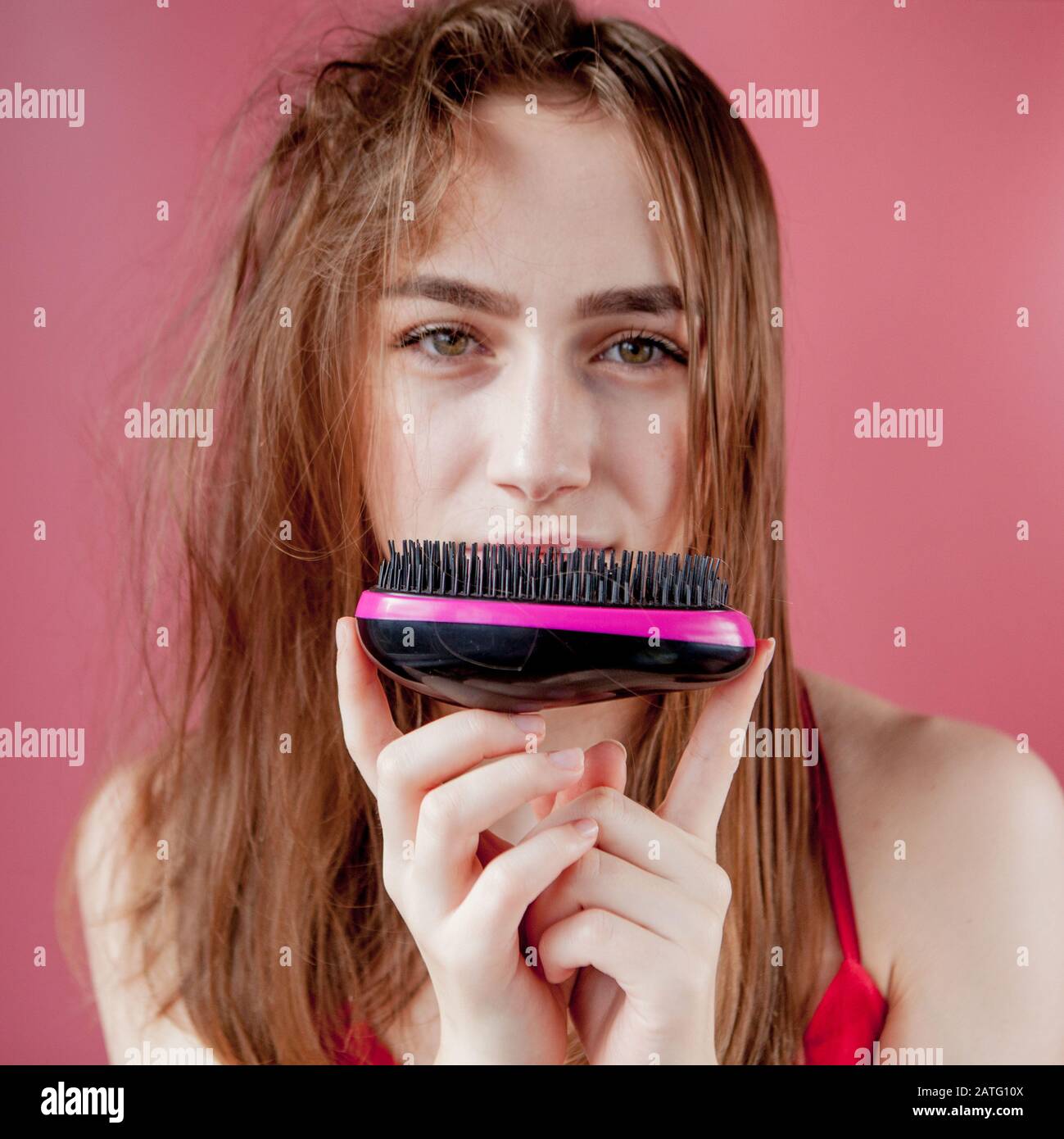 Young beautiful girl having problems while hair on pink background ...