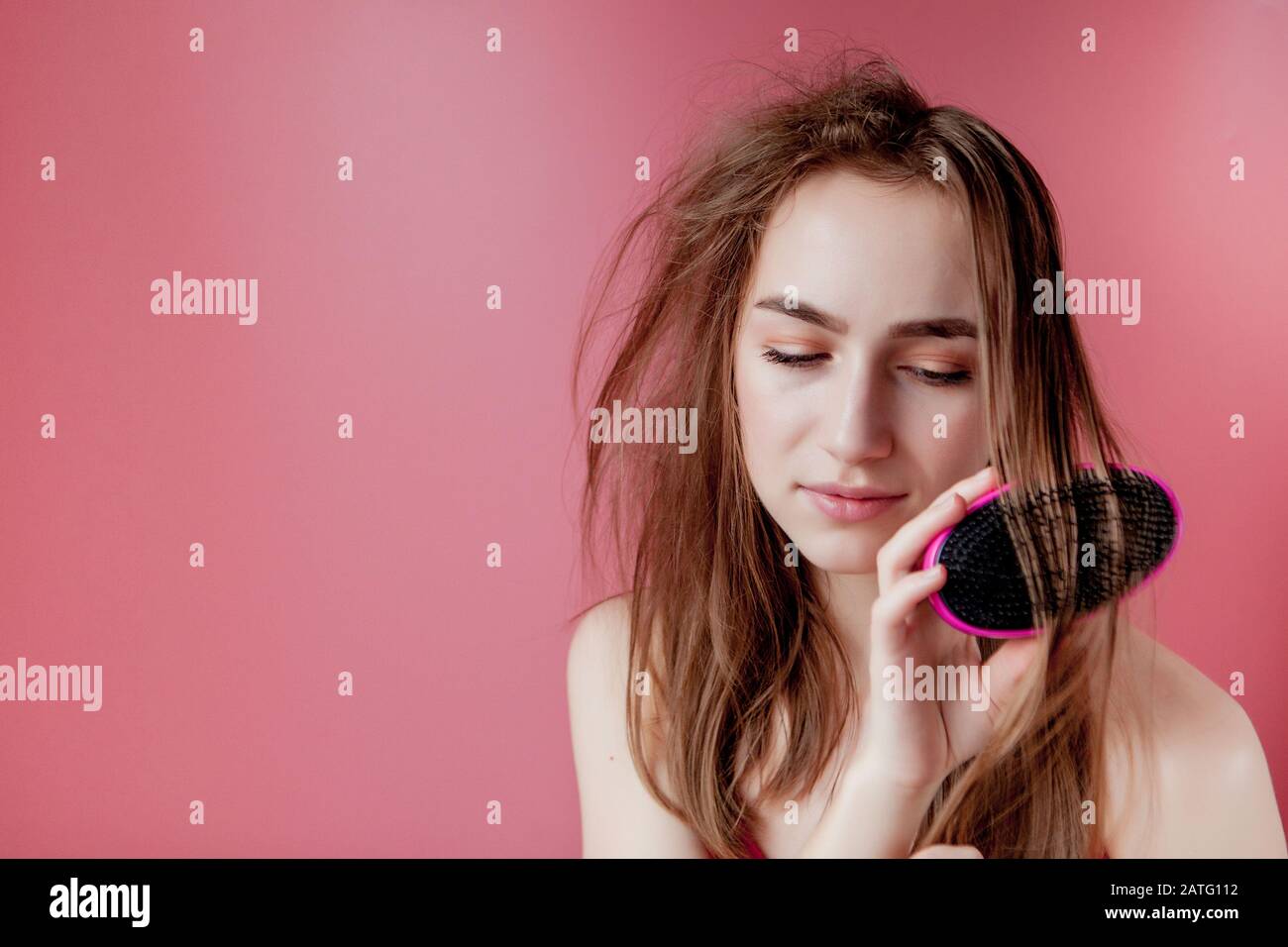 Young beautiful girl having problems while hair on pink background ...