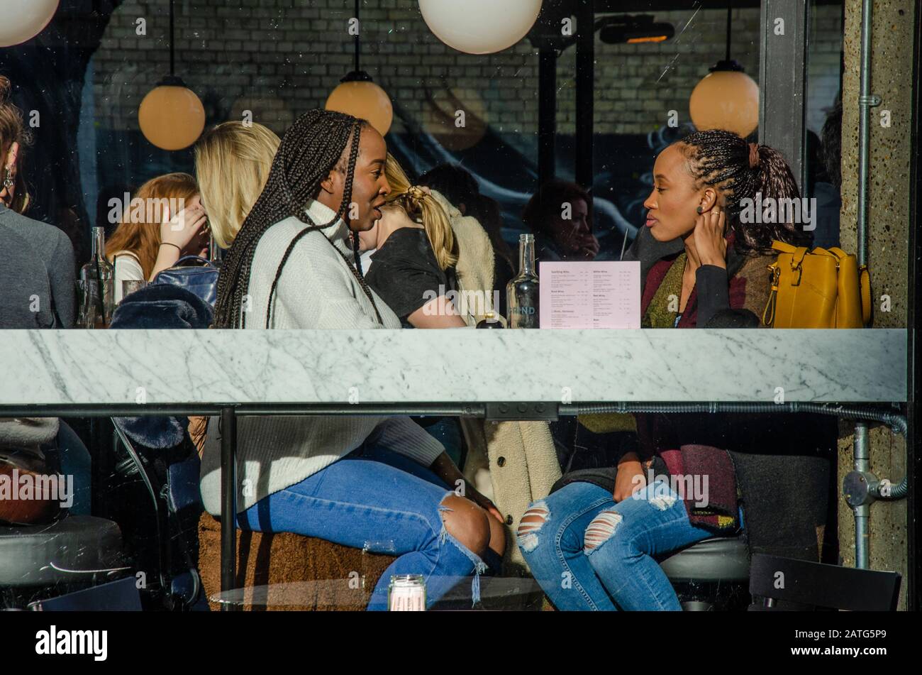 Friends socialise together in a bar in London and sit in the window ...