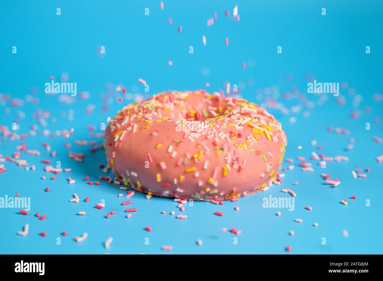 Sprinkles falling from top on Tasty pink strawberry donut. Delicious ...