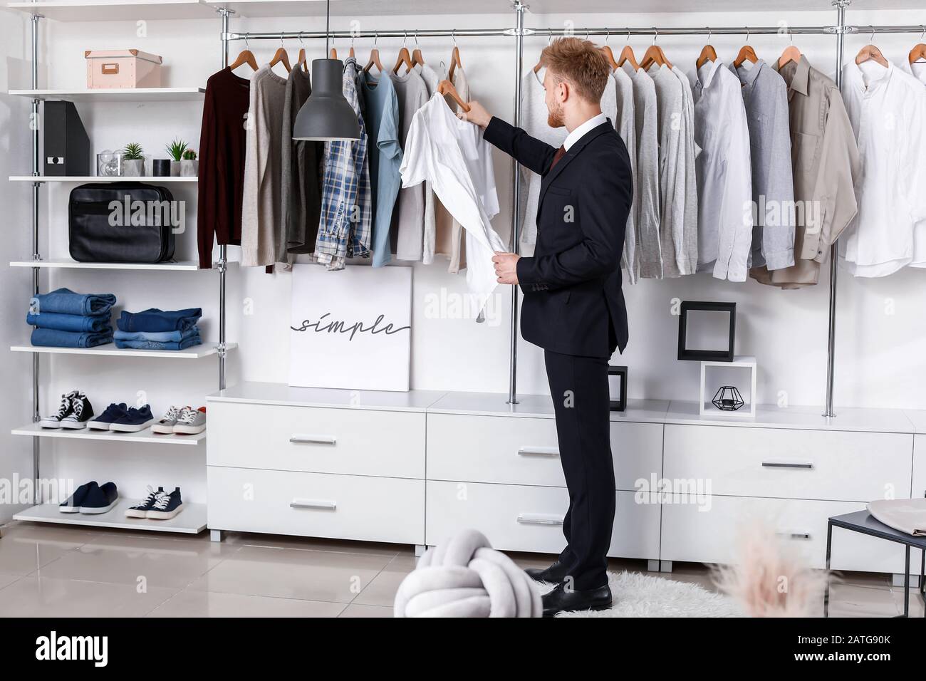 Handsome man choosing clothes in dressing room Stock Photo - Alamy