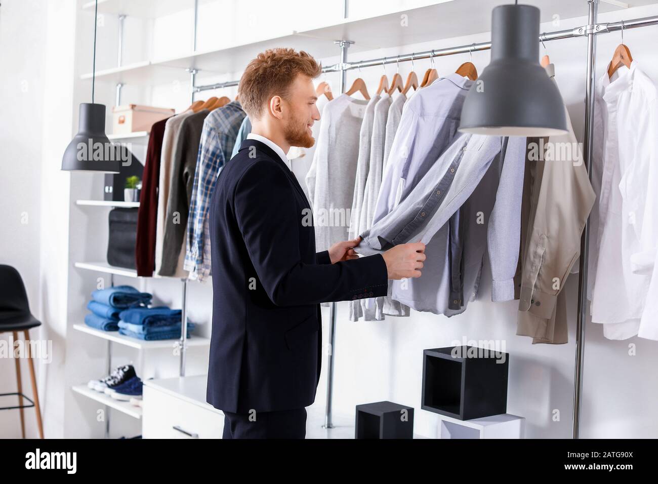 Handsome man choosing clothes in dressing room Stock Photo - Alamy