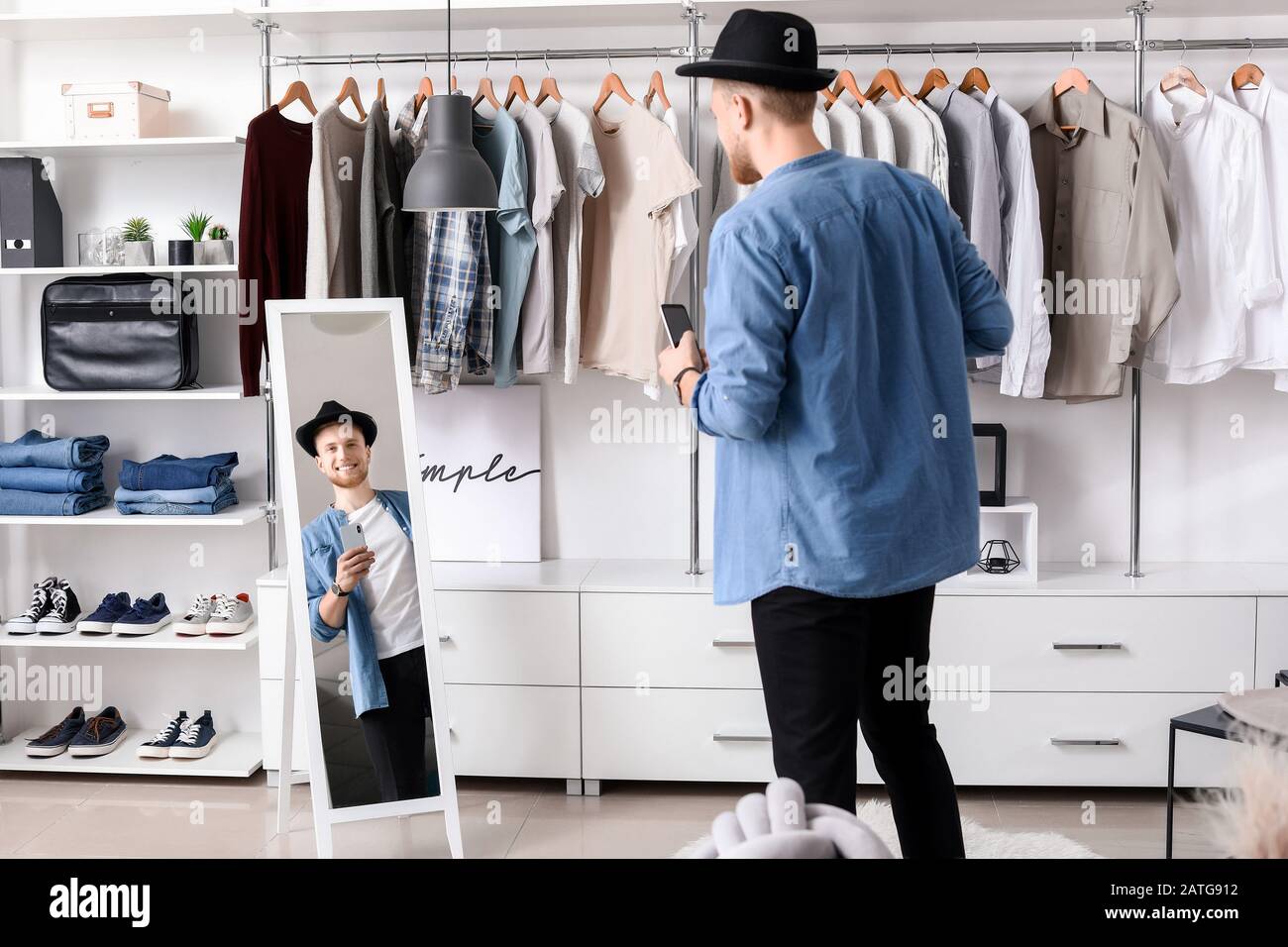 Handsome man trying on stylish clothes in dressing room Stock Photo - Alamy