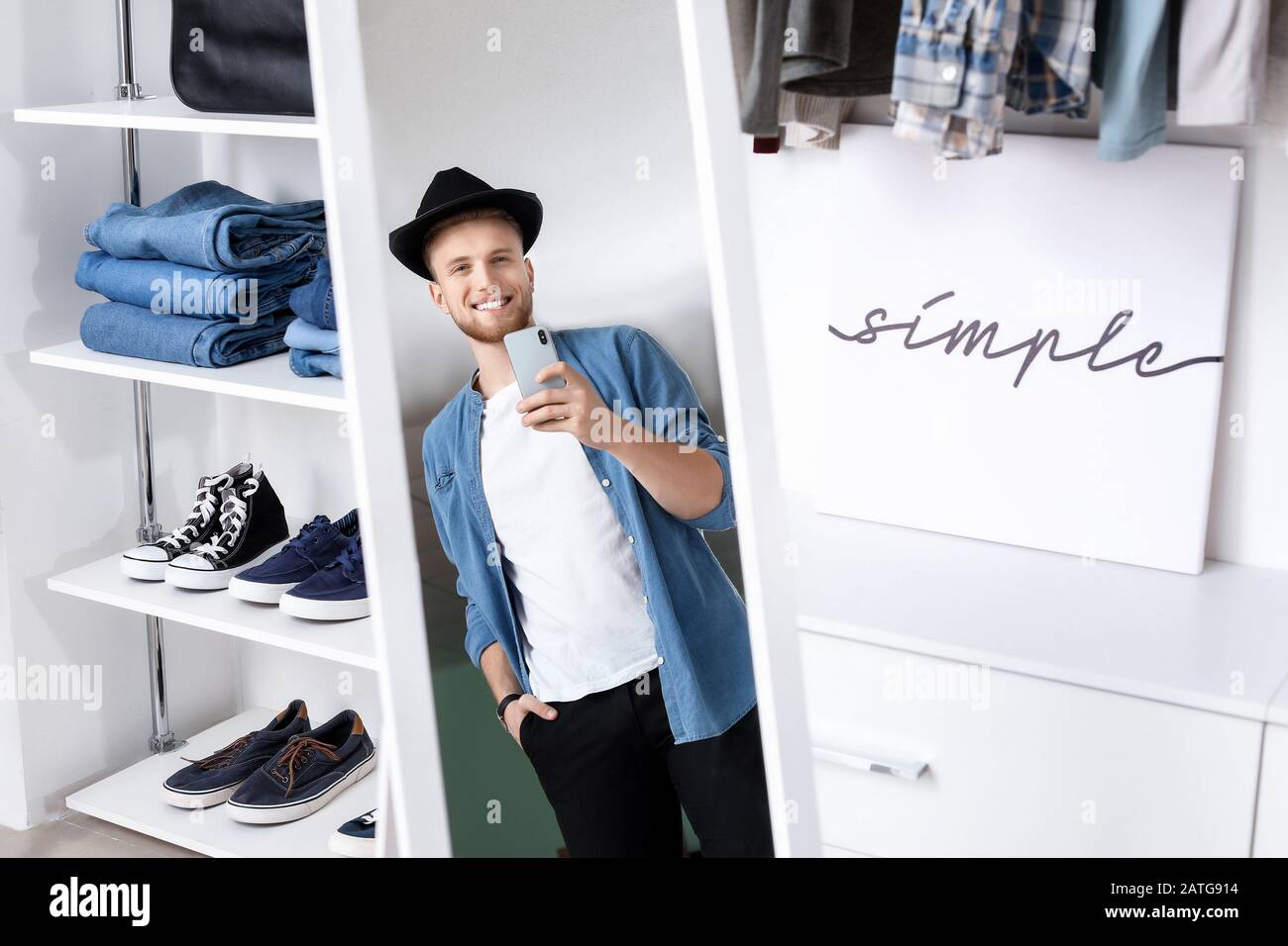 Handsome man trying on stylish clothes in dressing room Stock Photo - Alamy