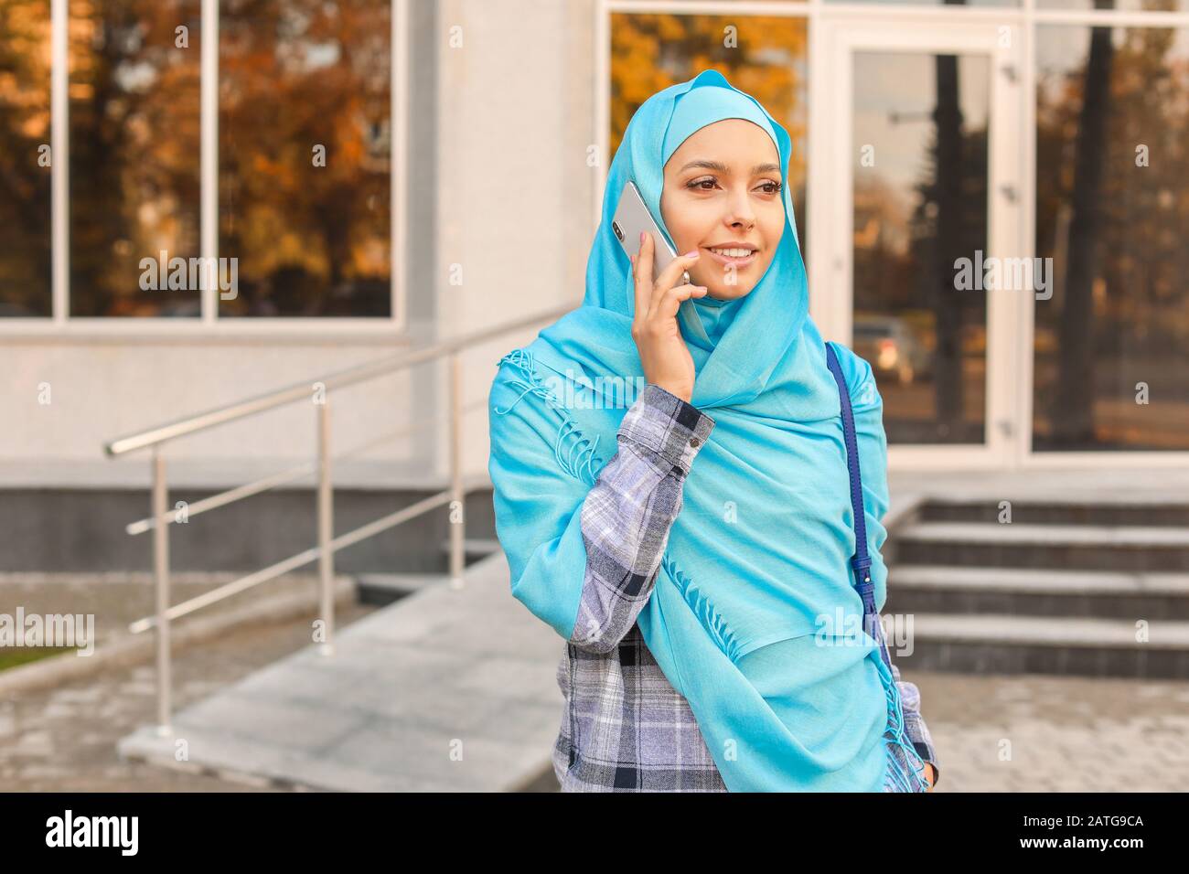 Beautiful young Muslim woman talking by phone outdoors Stock Photo - Alamy