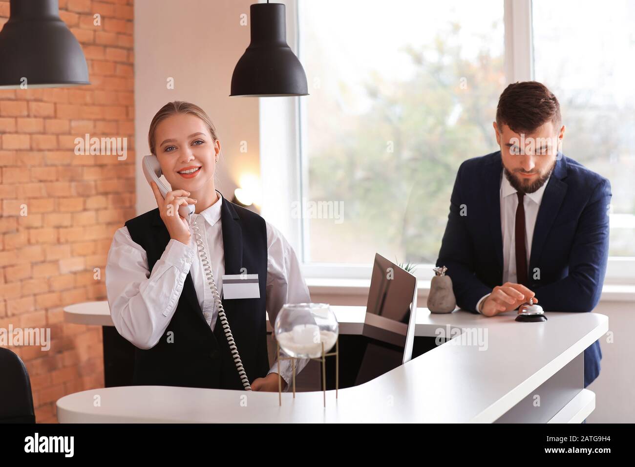 Young female receptionist talking by telephone at desk in hotel Stock ...