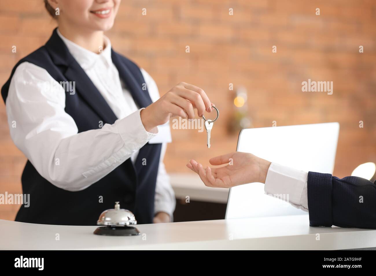 Female receptionist handing room key to woman in hotel Stock Photo - Alamy