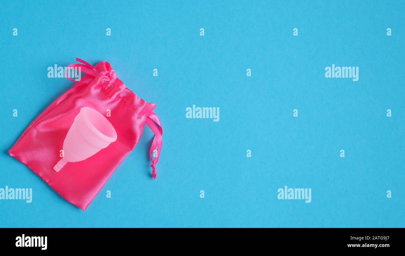 Reusable menstrual cup on blue background with copy space. Alternative ...