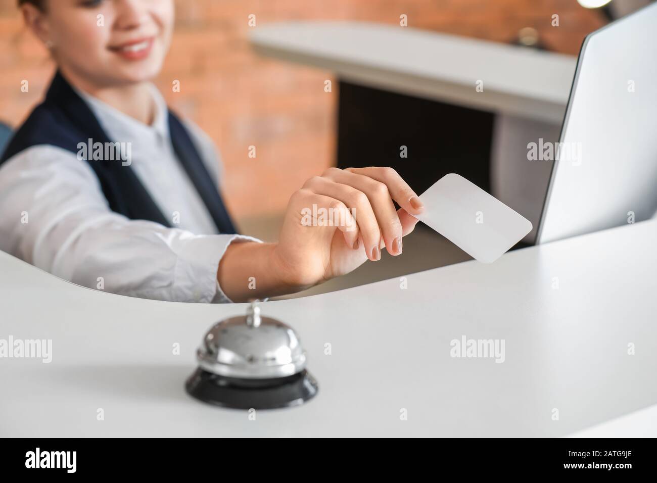 Young female receptionist with card at desk in hotel Stock Photo - Alamy