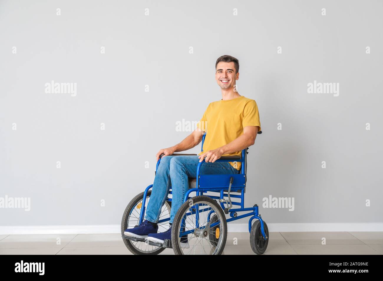 Handicapped young man in wheelchair near light wall Stock Photo - Alamy