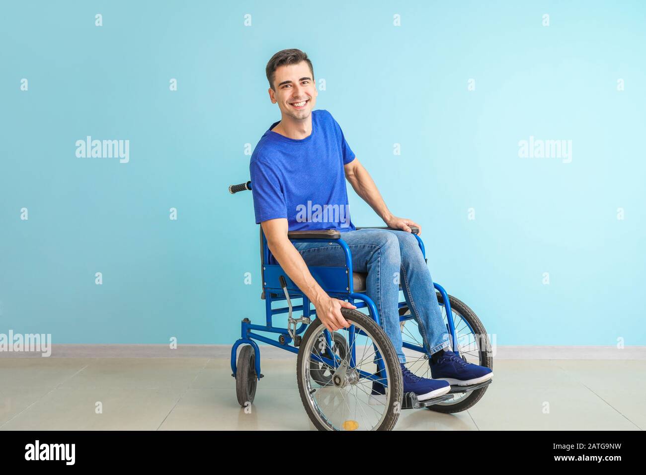 Handicapped young man in wheelchair near color wall Stock Photo - Alamy