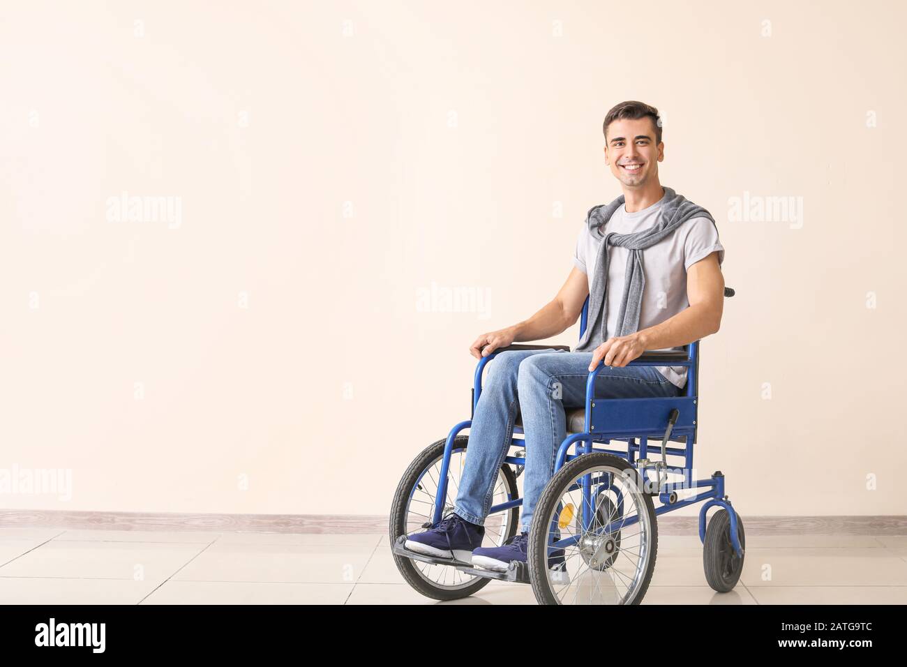 Handicapped young man in wheelchair near color wall Stock Photo - Alamy