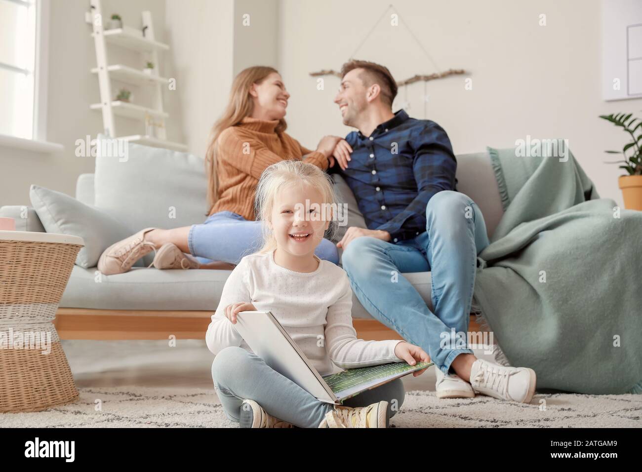 Cute little girl with parents resting at home Stock Photo - Alamy
