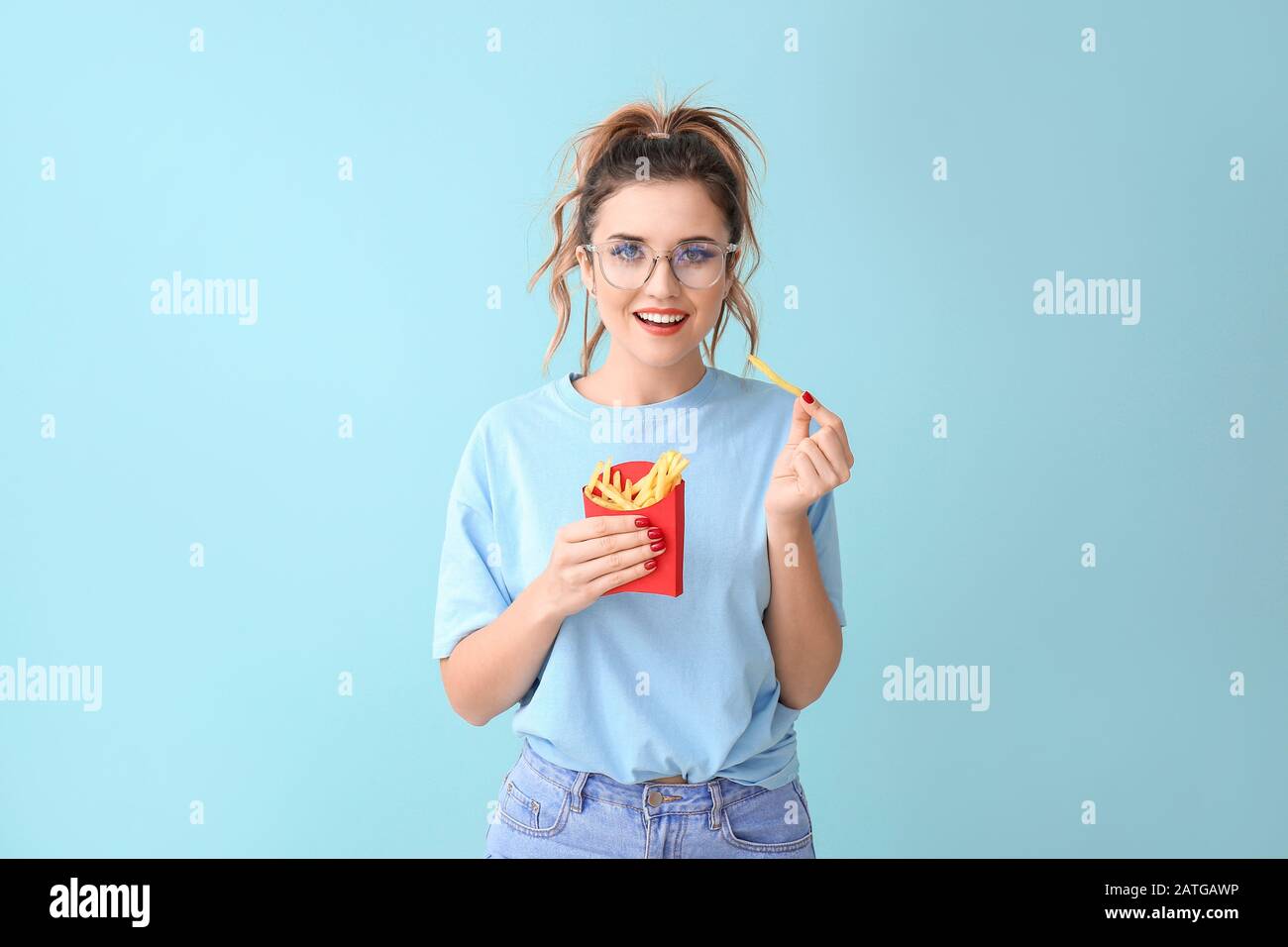 Portrait of beautiful young woman with french fries on color background ...