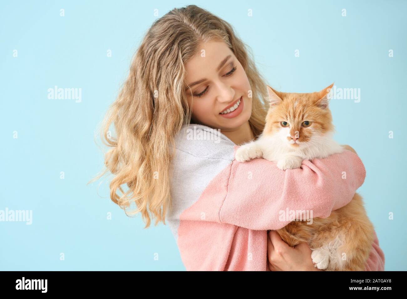 Beautiful young woman with cute cat on color background Stock Photo - Alamy
